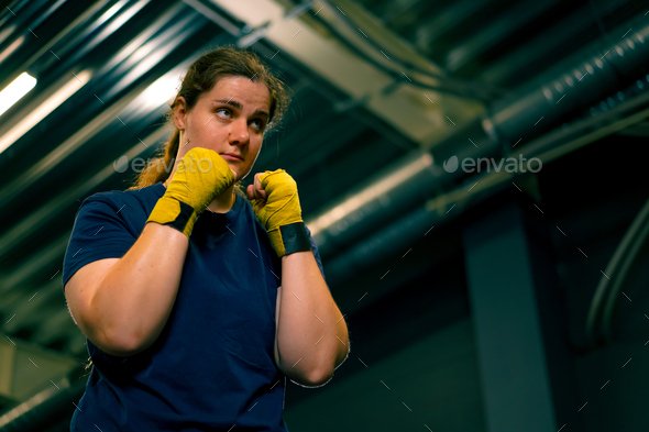 portrait focused Boxer girl yellow boxing bandages standing in a boxing ...