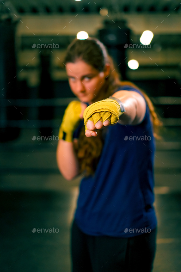 portrait focused Boxer girl in yellow boxing bandages standing in a ...