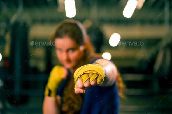 portrait focused Boxer girl in yellow boxing bandages standing in a ...
