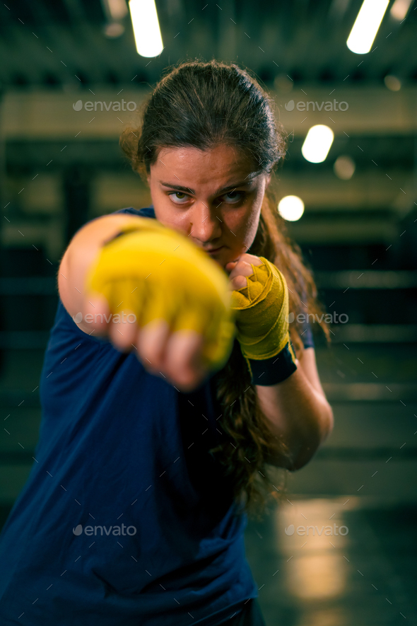 portrait focused Boxer girl in yellow boxing bandages standing in a ...
