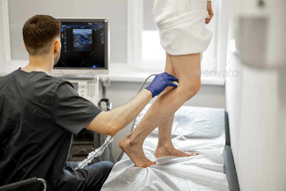 Ultrasound specialist scans veins on a woman's leg Stock Photo by RossHelen