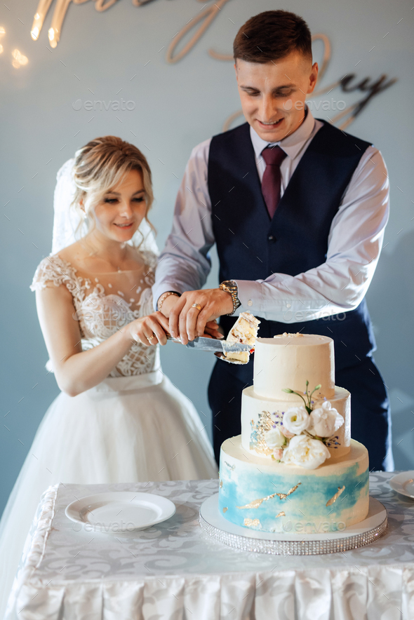 Bride and groom cutting and tasting wedding cake Stock Photo by Omelnickiy