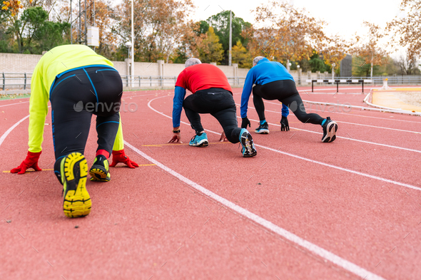 Senior Athletes at Starting Line Ready to Run on a Red Sports Track ...