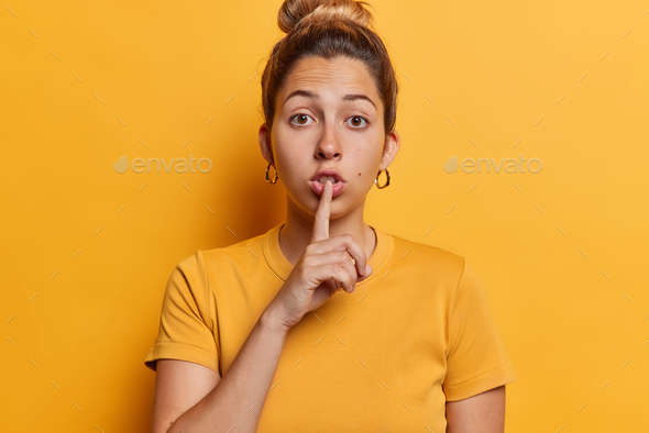 Silence and secrecy concept. Surprised young European woman keeps index ...