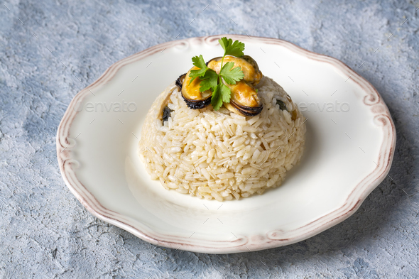 Mussel rice pilaf. Rice with mussels on small white plate on ceramic ...