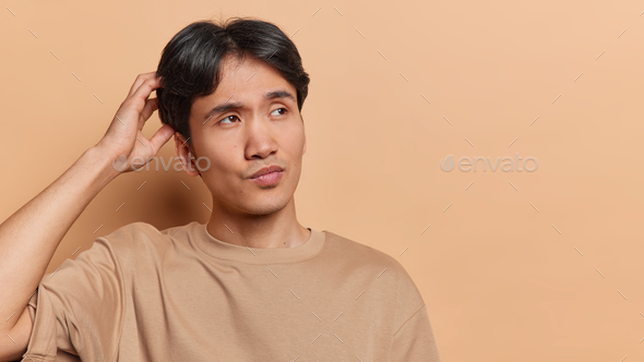 Horizontal shot of confused young Japanese man scratches head and ...