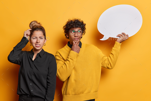 Couple have hesitant expressions hold blank speech bubble for your ...