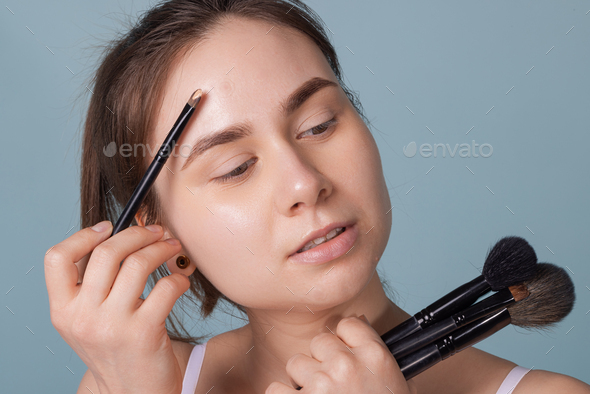 A girl with acne sticks an acne patch on her cheek. Using mini plaster ...