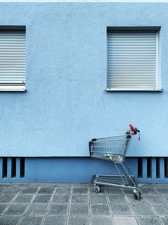 Empty Metal Shopping Cart Standing At Blue Geometric Wall With Closed ...