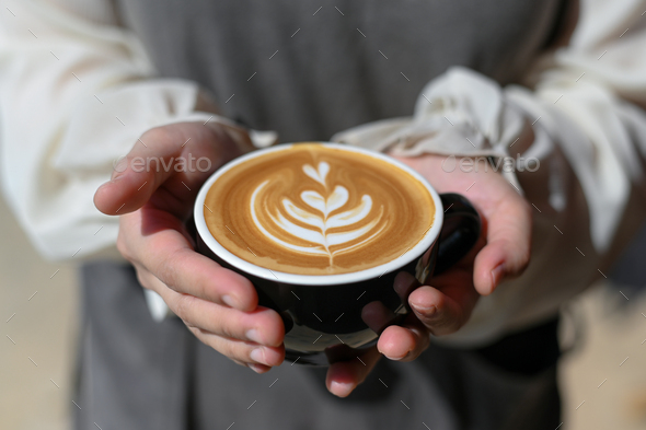 Heart-pattern latte coffee served in the hand of a barista. Stock Photo ...