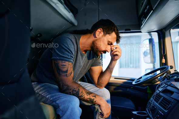 Sad professional truck driver in a cabin. Stock Photo by drazenphoto