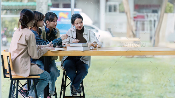 Group of young Asian college students sitting on a bench in a campus ...