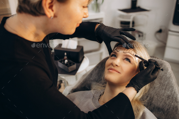 Cosmetician making measuring with ruler and getting ready to apply ...