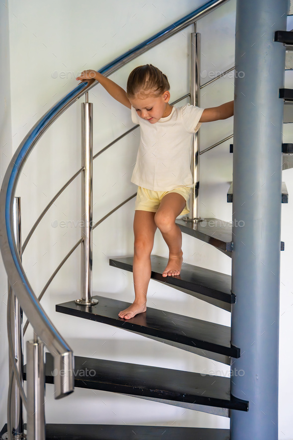 Portrait of little girl going down the stairs at home, child climbing ...
