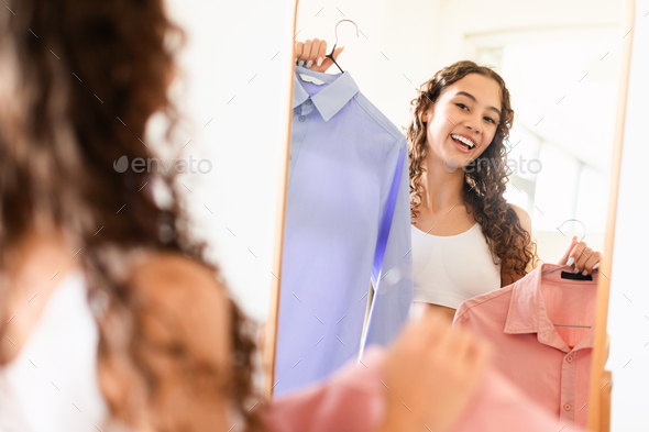 Cheerful Teen Girl Choosing Clothes And Outfits Near Mirror Indoors ...
