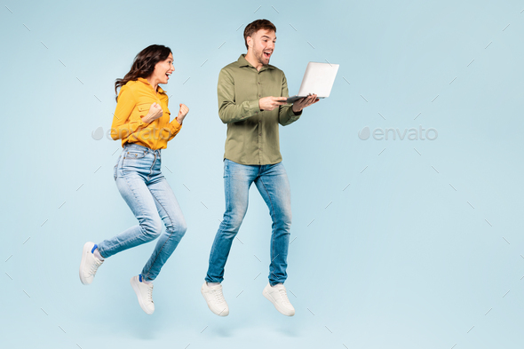 Dynamic couple jumping with joy and a laptop, expressing success Stock ...