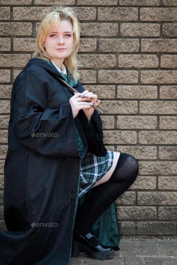 Blonde Caucasian female cosplayer dressed as a wizard with a magic wand ...