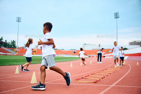 Black kid and his friends having PE class at the stadium. Stock Photo ...