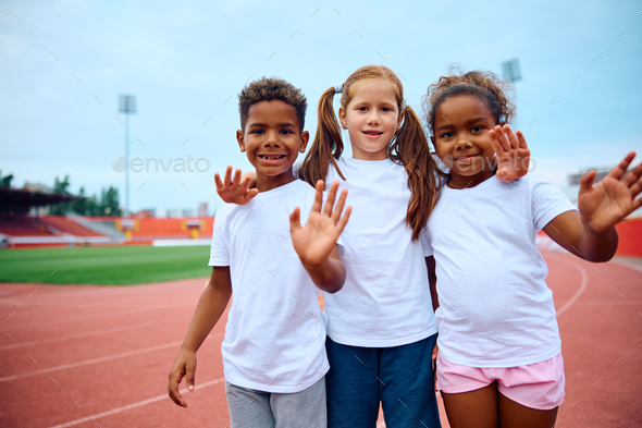 Multiracial group of kids waving at camera during exercise class at the ...