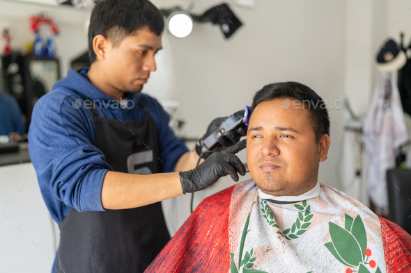 Latin young barber attending a client in a barber shop Stock Photo by ...