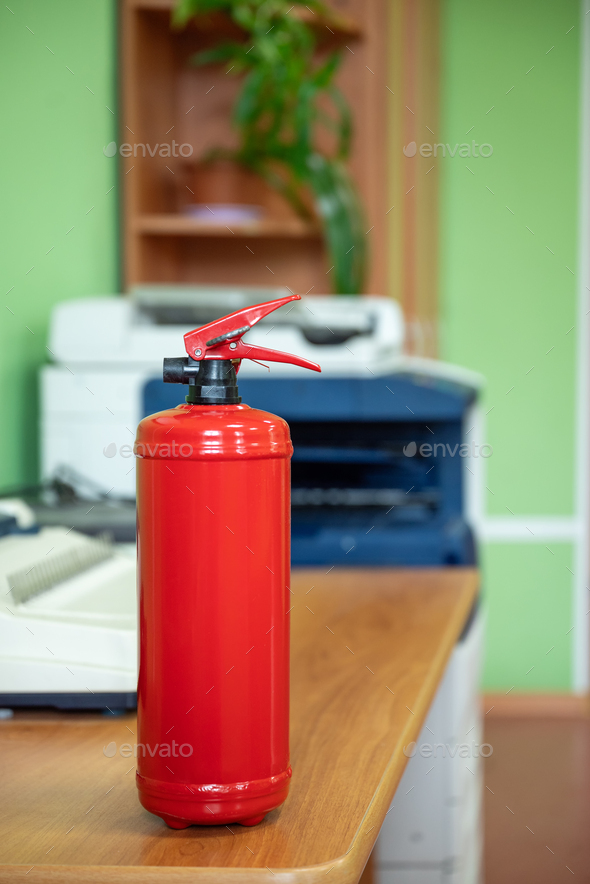 Fire extinguisher in workplace office. Fire safety Stock Photo by akifewas