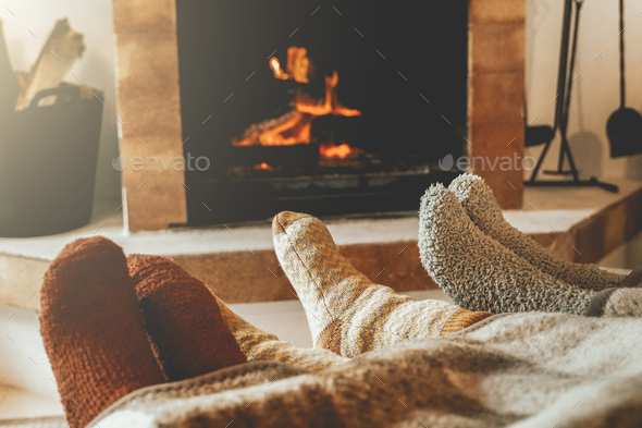 Family resting feet by fireplace. People warming feet with blanket and ...