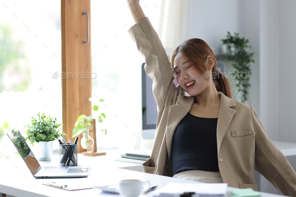 A business woman working in an office stretches to relax from work ...