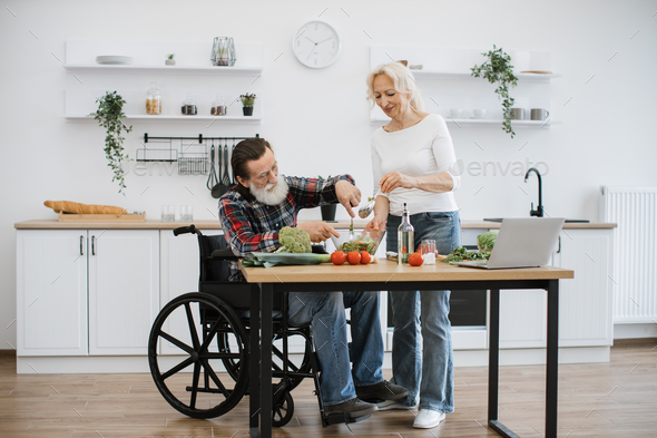 Old couple with disability spends time cooking breakfast in modern ...
