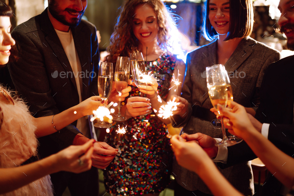 Glowing sparkles in hands. Group of happy people enjoying party with ...