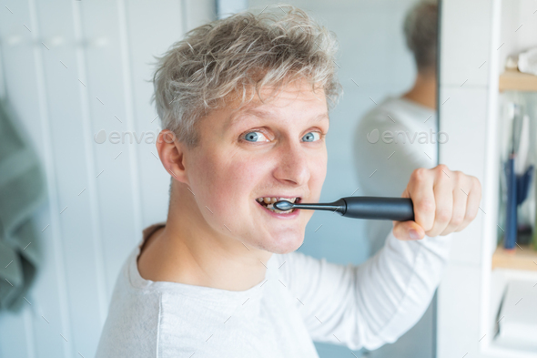 Close up portrait of Young Man is using electric ultrasound toothbrush ...