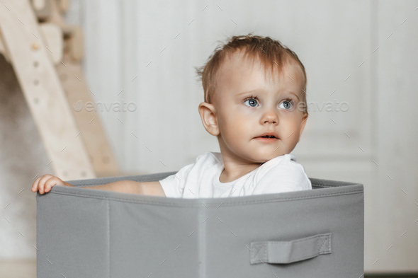 Cute little baby boy sitting inside box with big boxes full of toys on ...