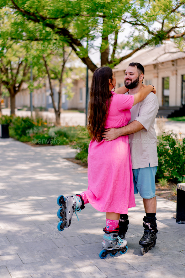 Young couple on rollerblades guy and girl cuddle during date in the ...