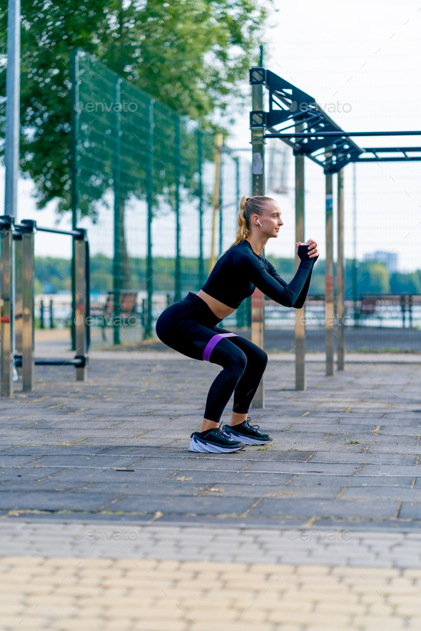 Beautiful girl in sports uniform performs exercises pump up her legs ...