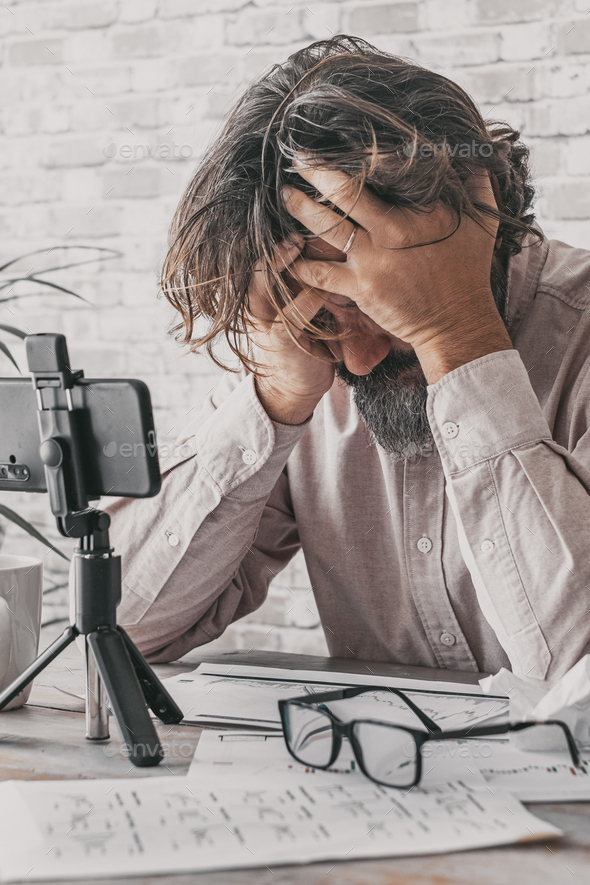 Man working at home on the table with desperate expression and posture ...