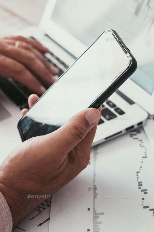 Close up of man hands with mobile phone and laptop computer. People ...