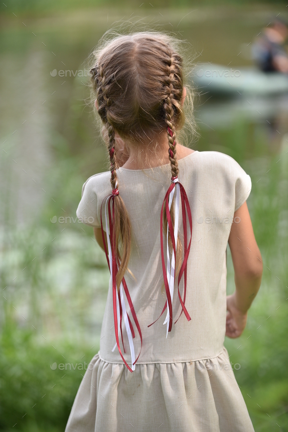 Little girl with braids and ribbons in her hair. Stock Photo by raimonds-k