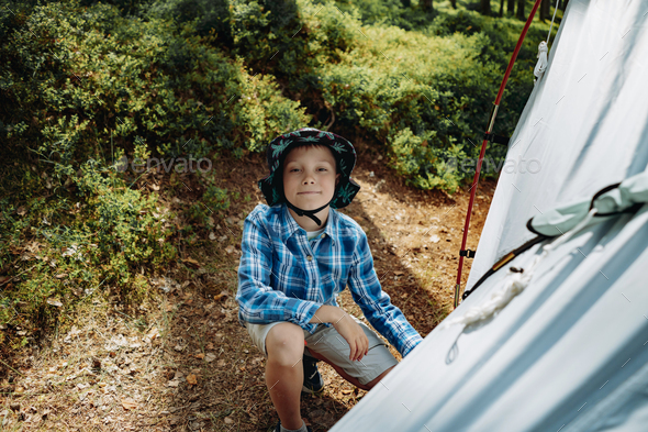 cute caucasian boy putting up a tent. Family camping concept Stock Photo by uraneva