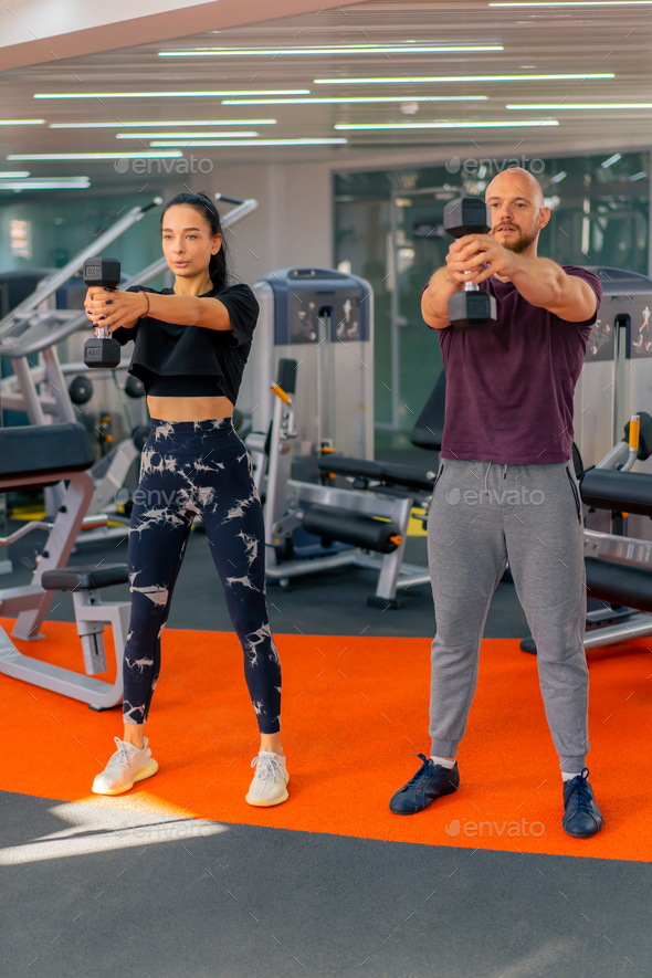 girl fitness trainer and bodybuilder doing exercises with dumbbells in ...