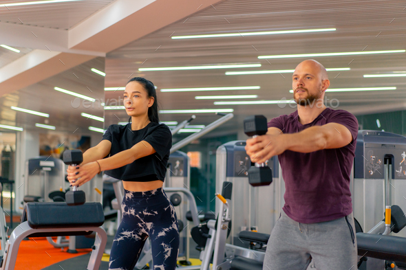 girl fitness trainer and bodybuilder doing exercises with dumbbells in ...