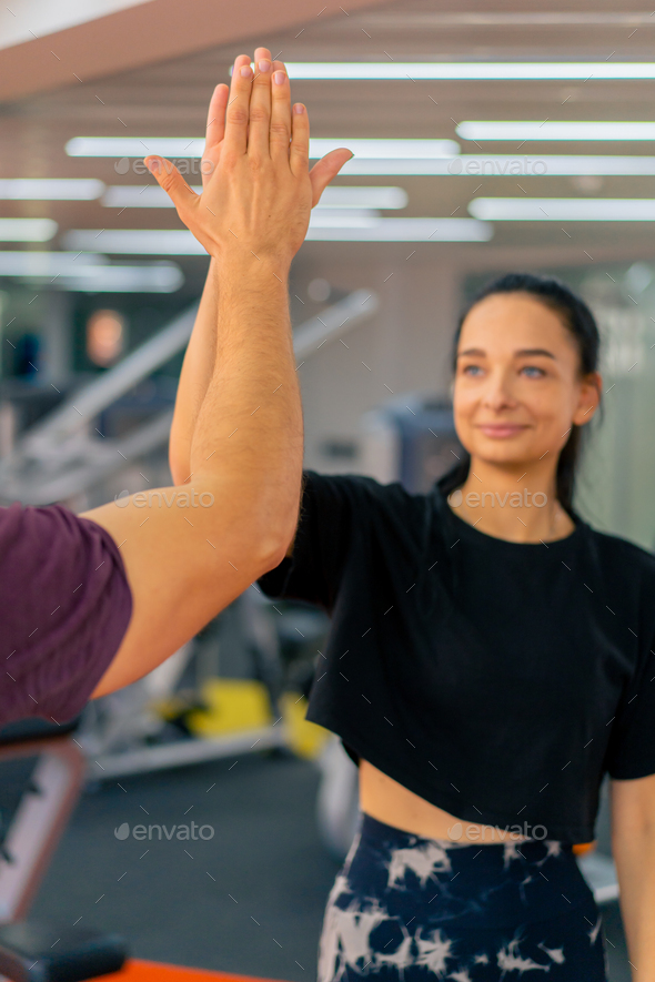 girl fitness trainer and bodybuilder in the gym give each other a high ...