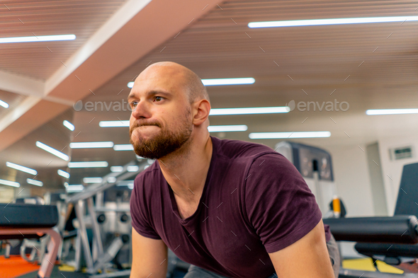 stressed face of a bodybuilder doing strength exercises with a barbell ...