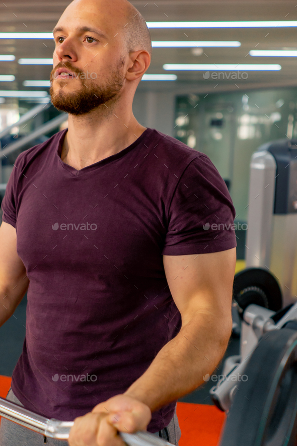 stressed face of a bodybuilder doing strength exercises with a barbell ...