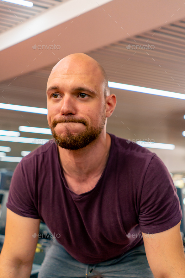 stressed face of a bodybuilder doing strength exercises with a barbell ...
