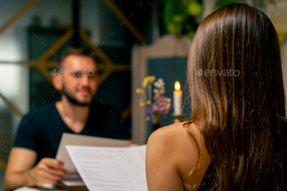 guy and girl sitting in an Italian restaurant looking at the menu and ...