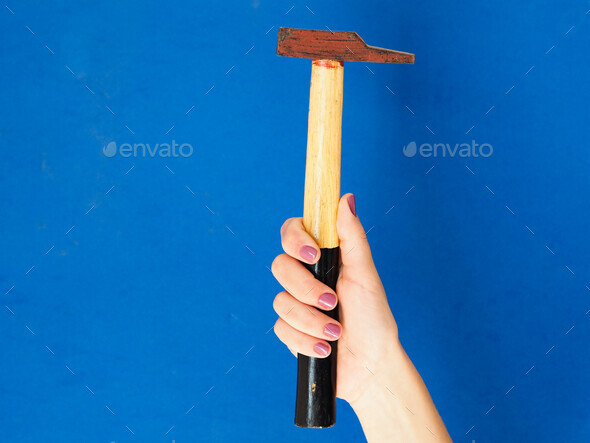 Girl's hand with nails painted purple wielding a hammer on a blue ...