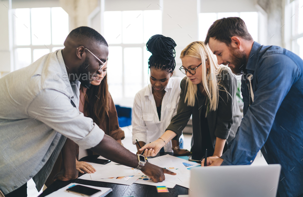 Diverse colleagues gathering around table and working on project in ...