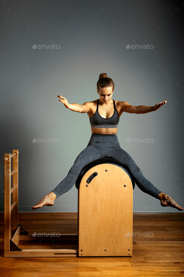 Pilates trainer exercises on a pilates barrel. Body training, perfect ...