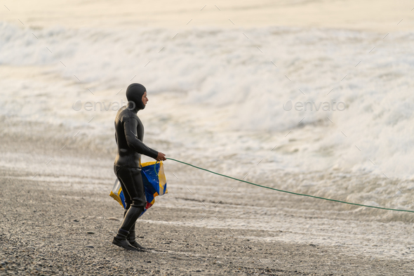 Fisherman in wetsuit using rope to drag fish Stock Photo by GSR-PhotoStudio