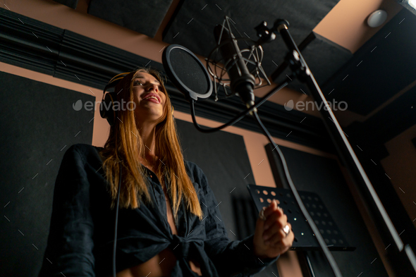 girl singer singing in a recording studio with headphones in front of a ...