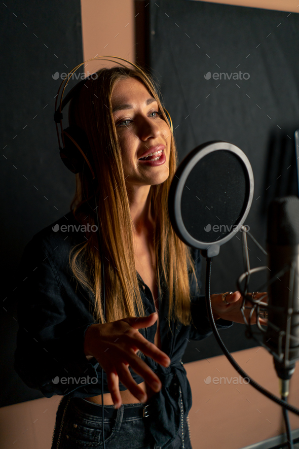 girl singer singing in a recording studio wearing headphones in front ...